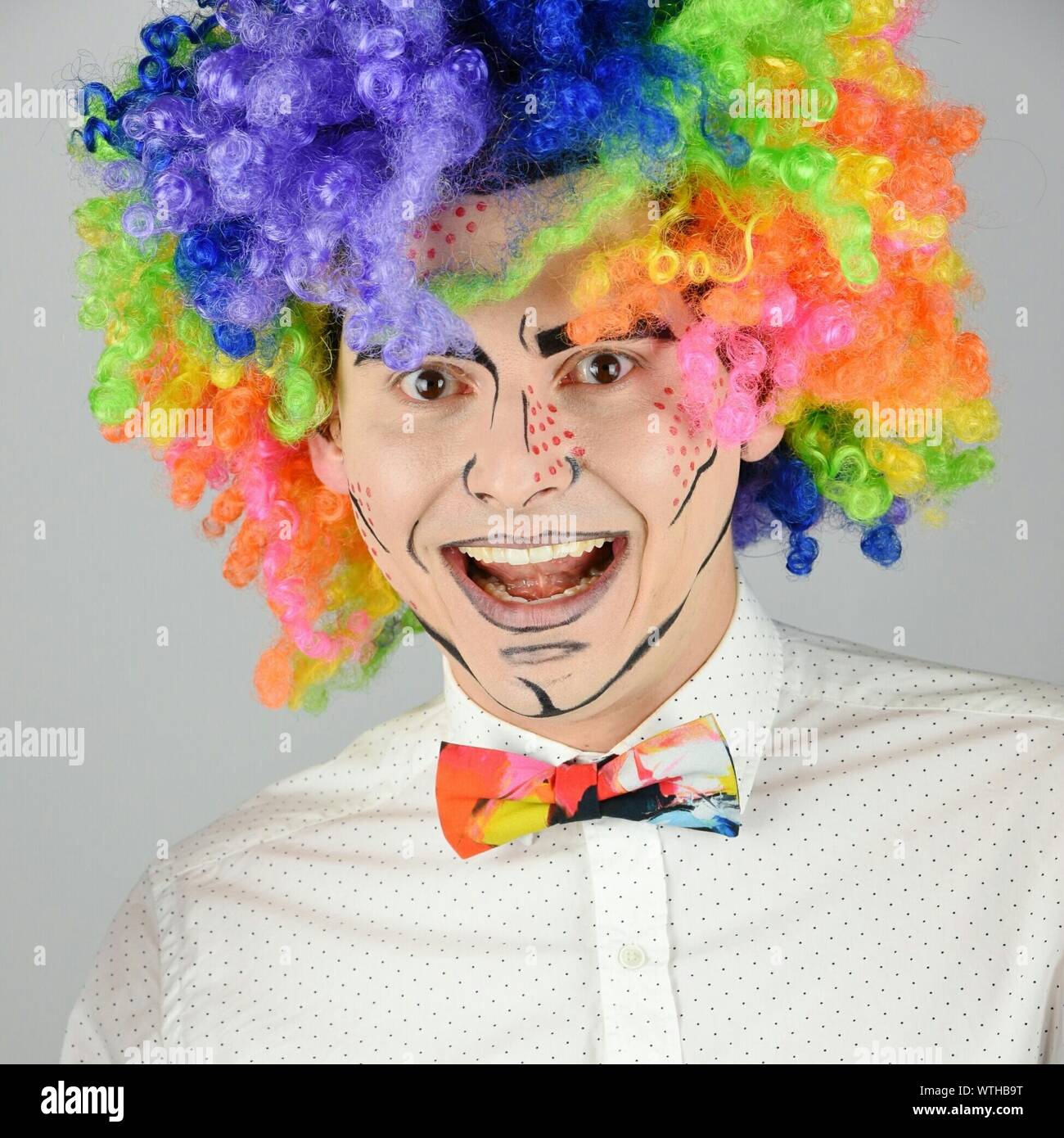 Portrait Of Man Wearing Clown Costume Against White Background Stock