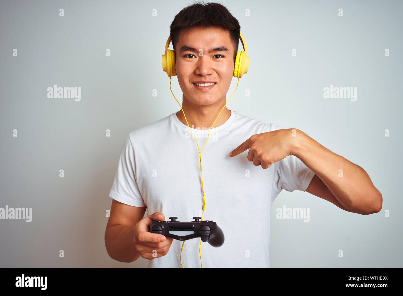 Young asian chinese gamer man playing video game standing over isolated ...