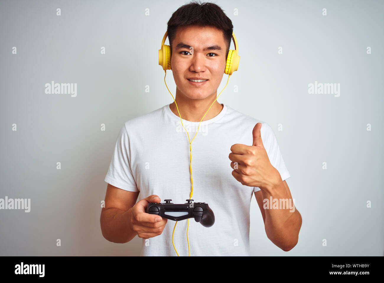 Young asian chinese gamer man playing video game standing over isolated ...