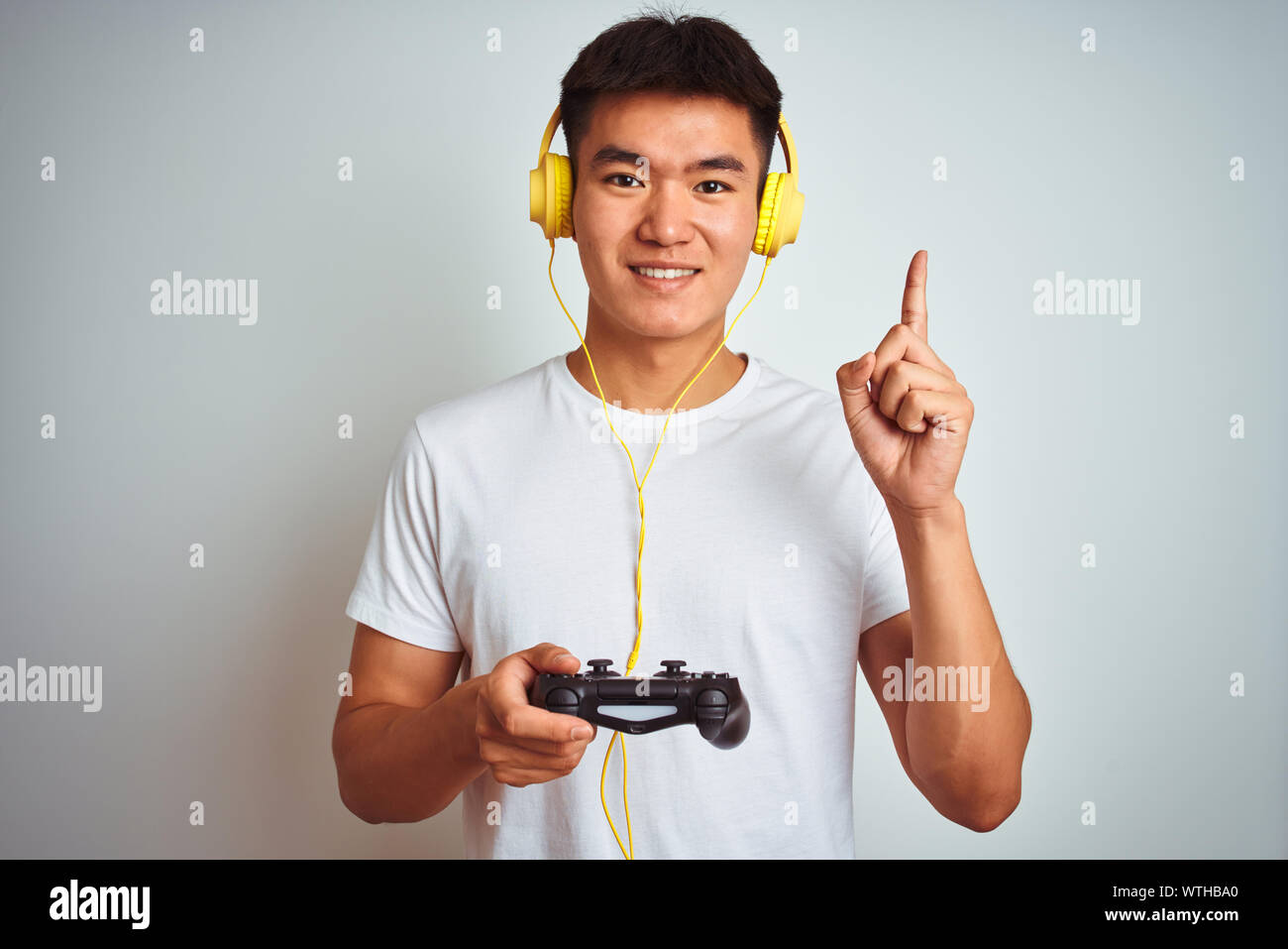 Young asian chinese gamer man playing video game standing over isolated ...