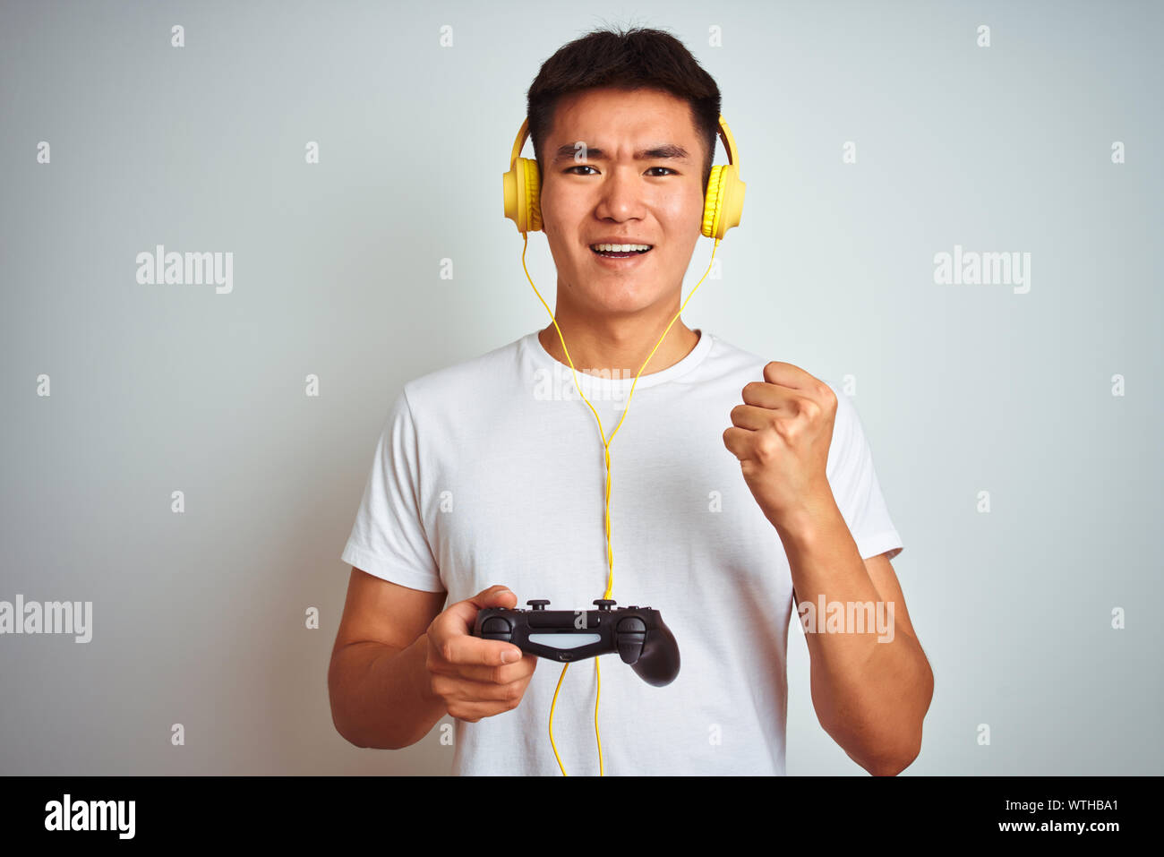 Young asian chinese gamer man playing video game standing over isolated ...