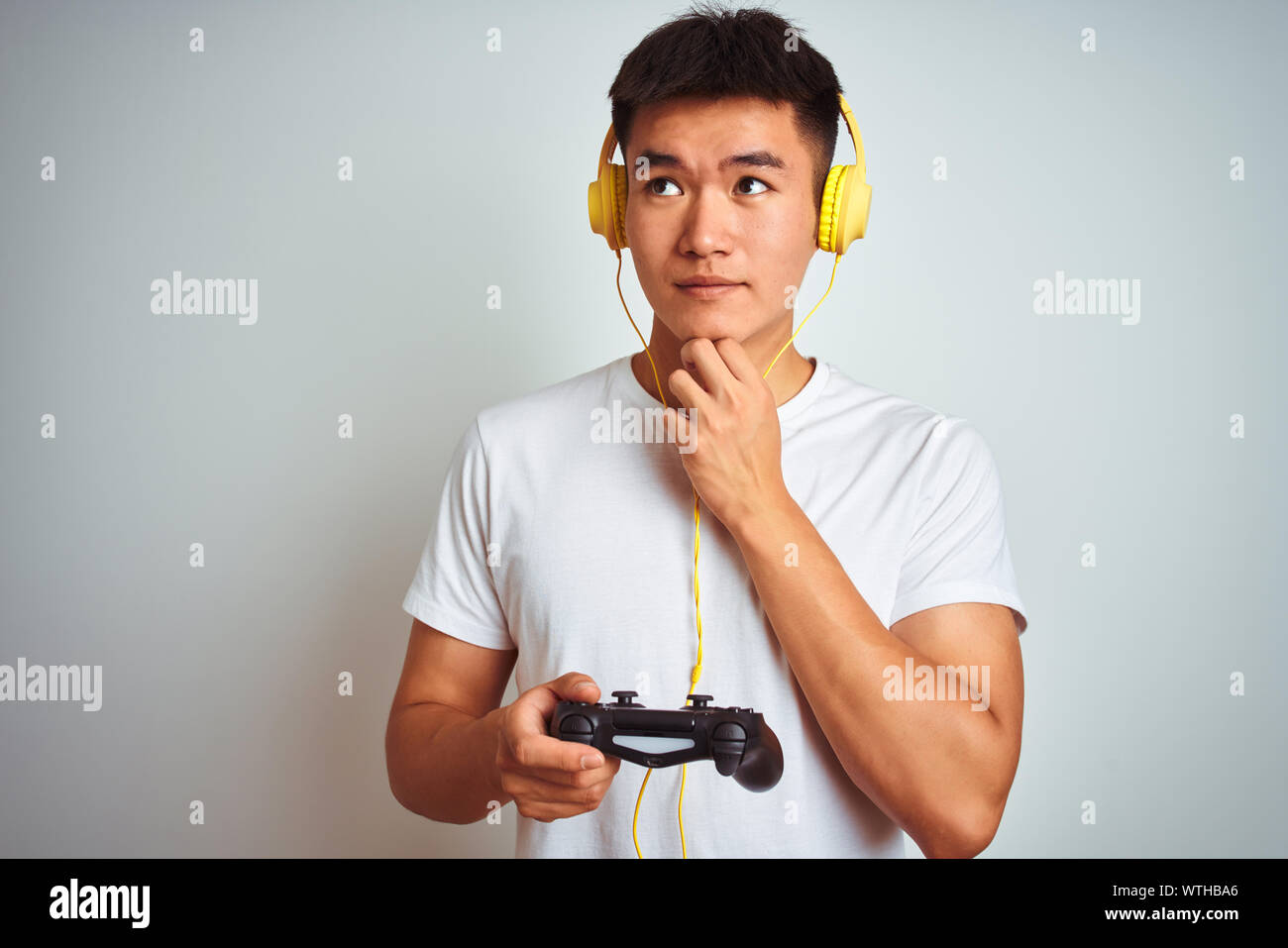 Young asian chinese gamer man playing video game standing over isolated ...