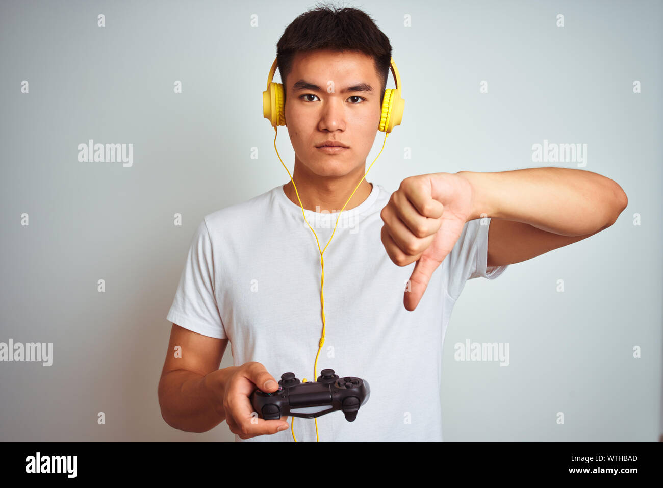 Young asian chinese gamer man playing video game standing over isolated ...
