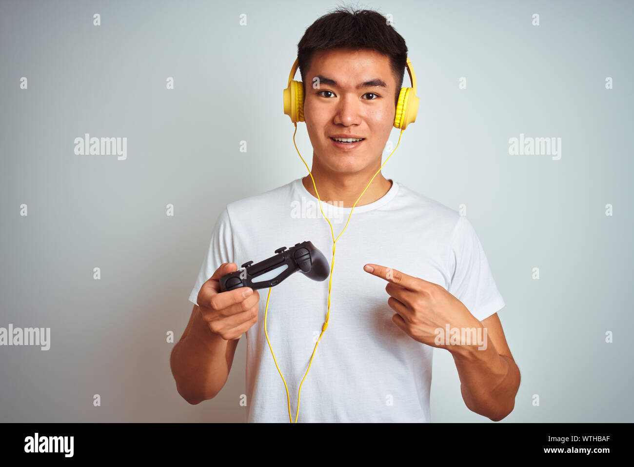 Young asian chinese gamer man playing video game standing over isolated ...