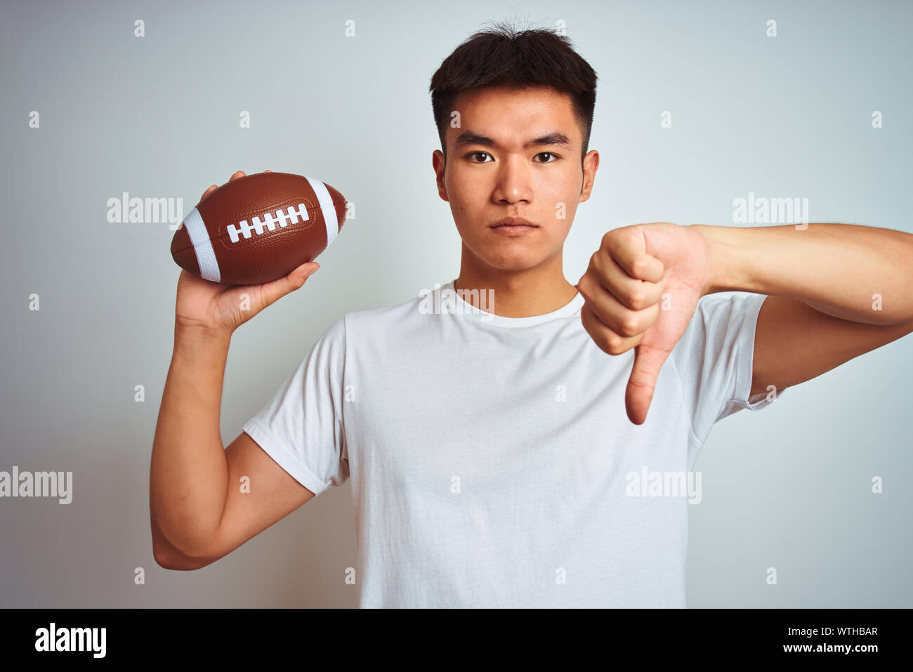 Young asian chinese sportsman holding rugby ball standing over isolated ...