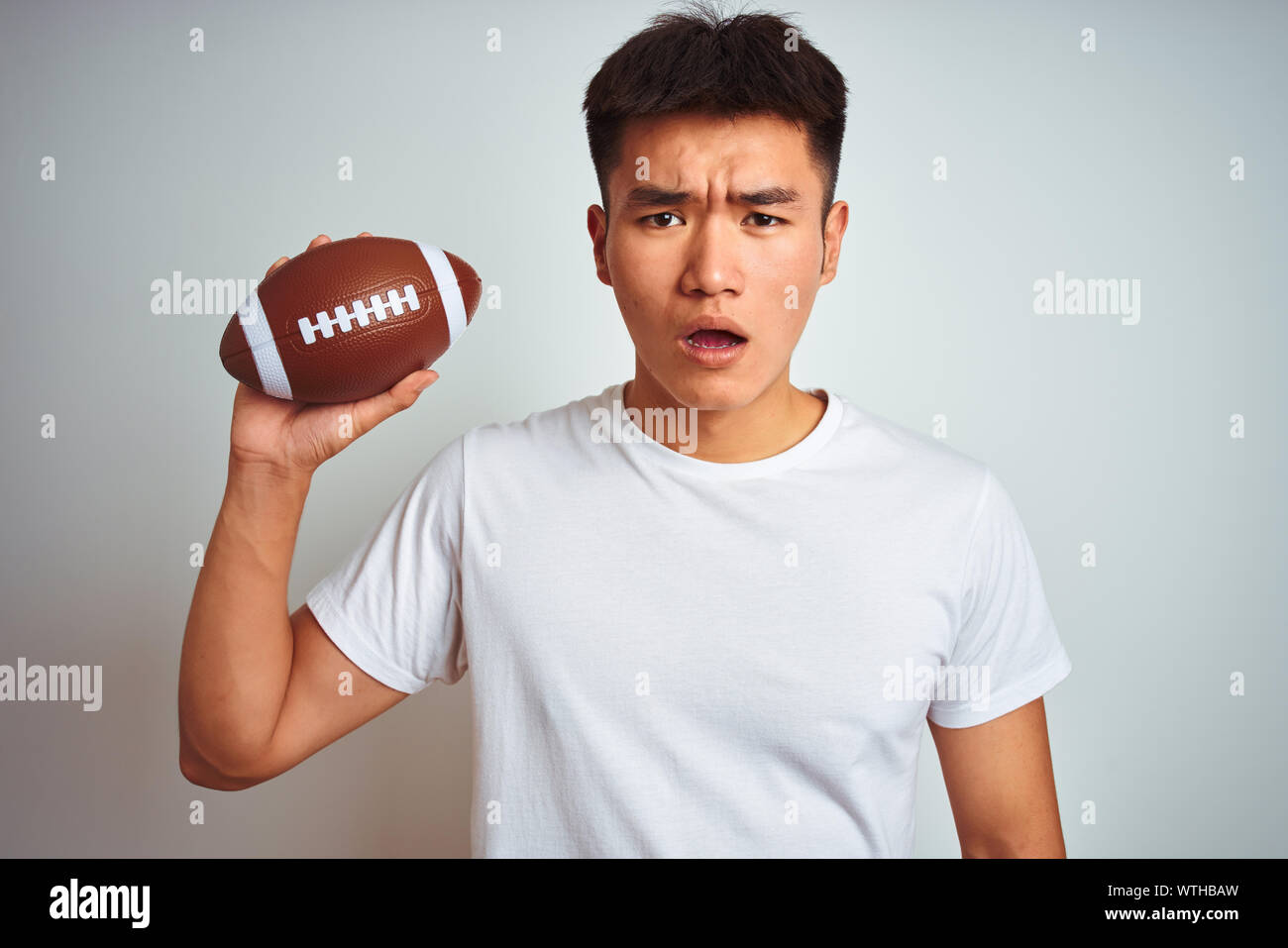 Young asian chinese sportsman holding rugby ball standing over isolated ...