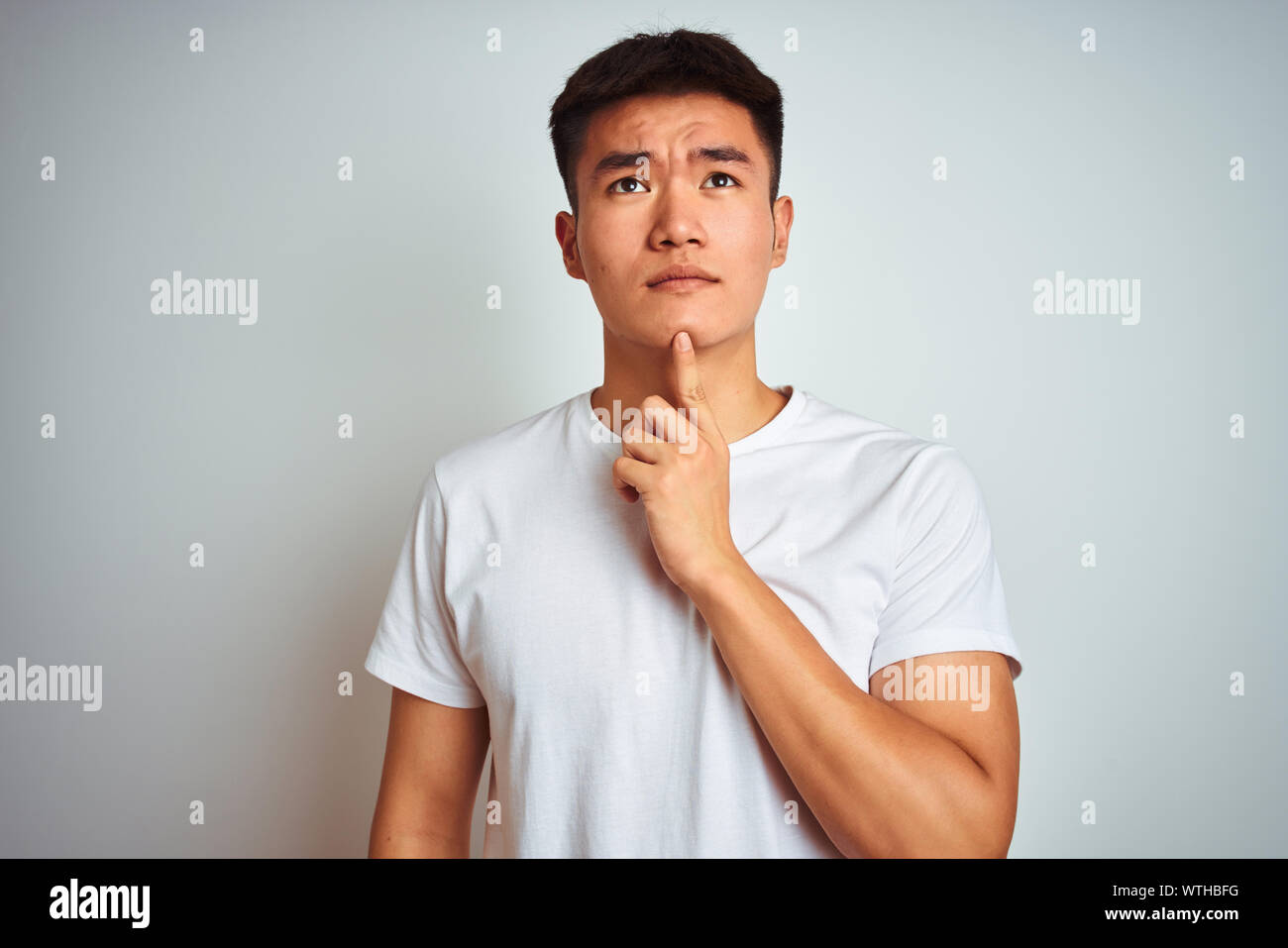 Young asian chinese man wearing t-shirt standing over isolated white ...