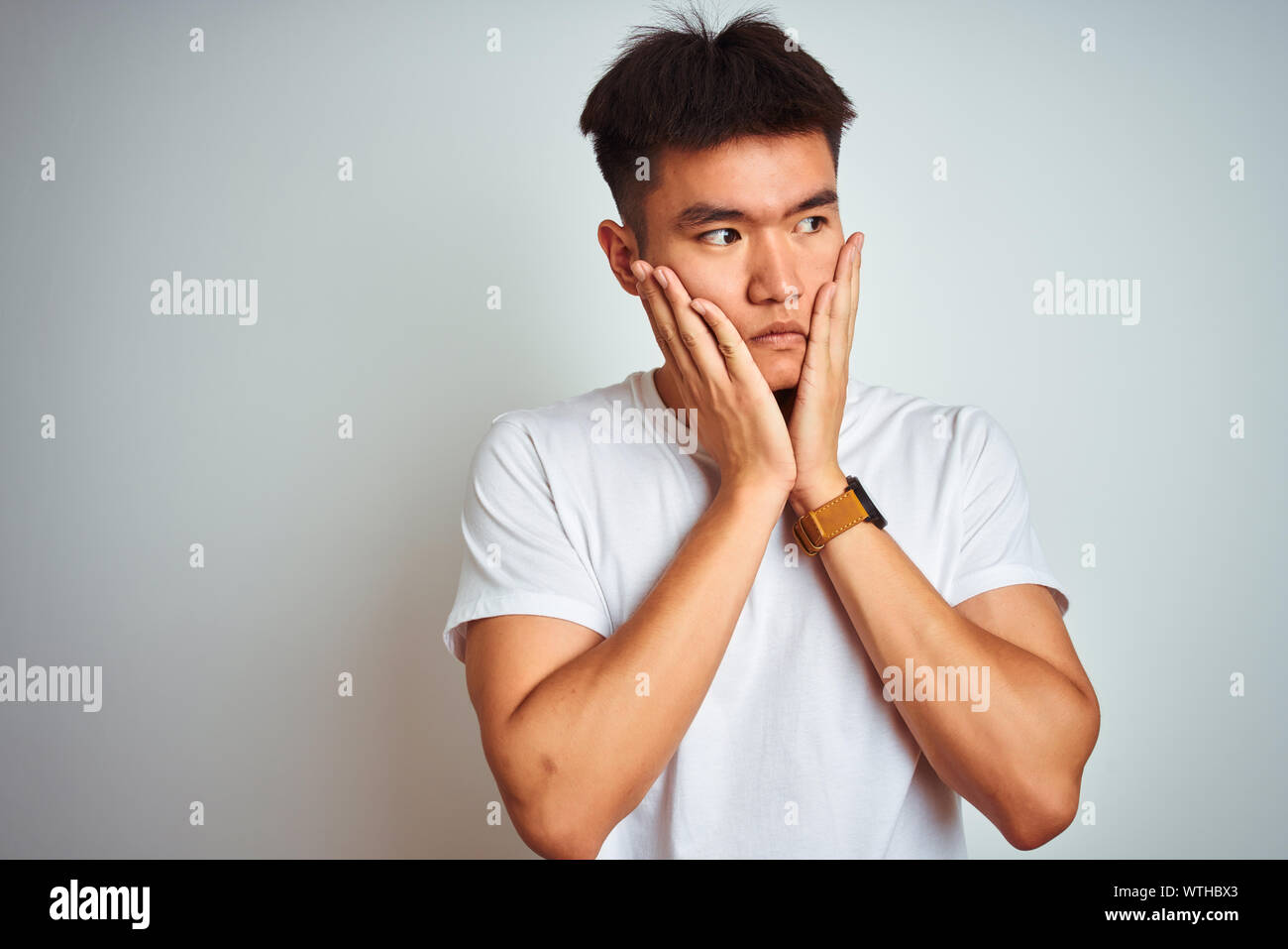 Young asian chinese man wearing t-shirt standing over isolated white ...