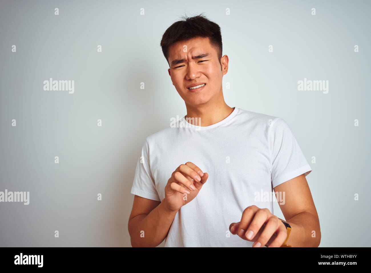 Young asian chinese man wearing t-shirt standing over isolated white ...
