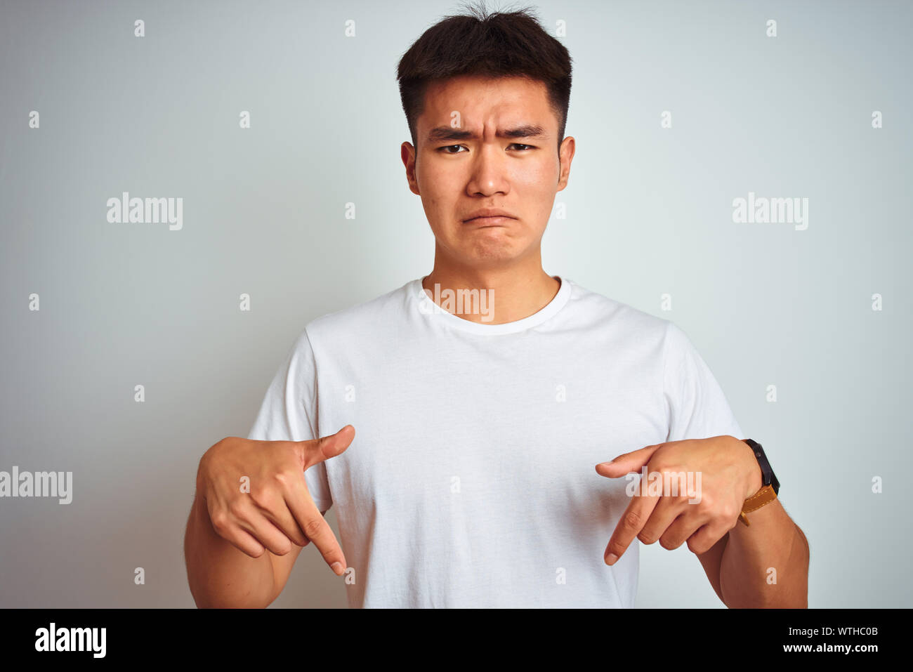 Young asian chinese man wearing t-shirt standing over isolated white ...