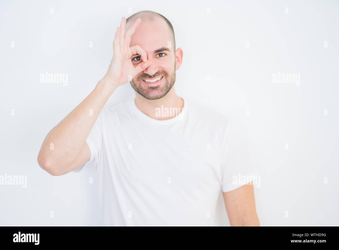 Young bald man over white isolated background doing ok gesture with ...