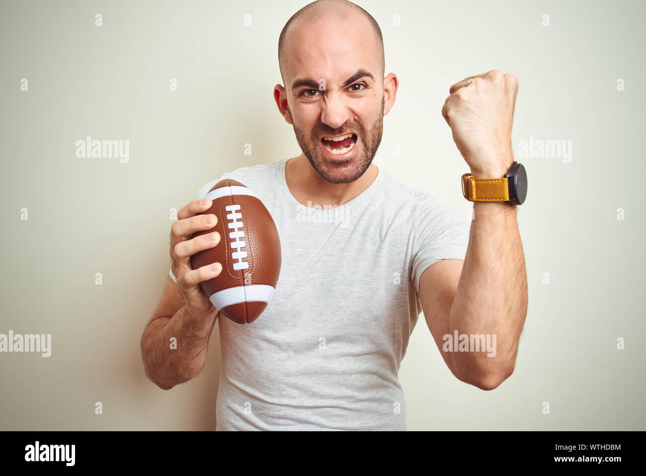 Young man holding rugby american football ball over isolated background ...