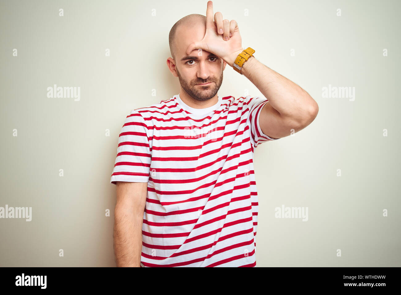 Young bald man with beard wearing casual striped red t-shirt over white ...