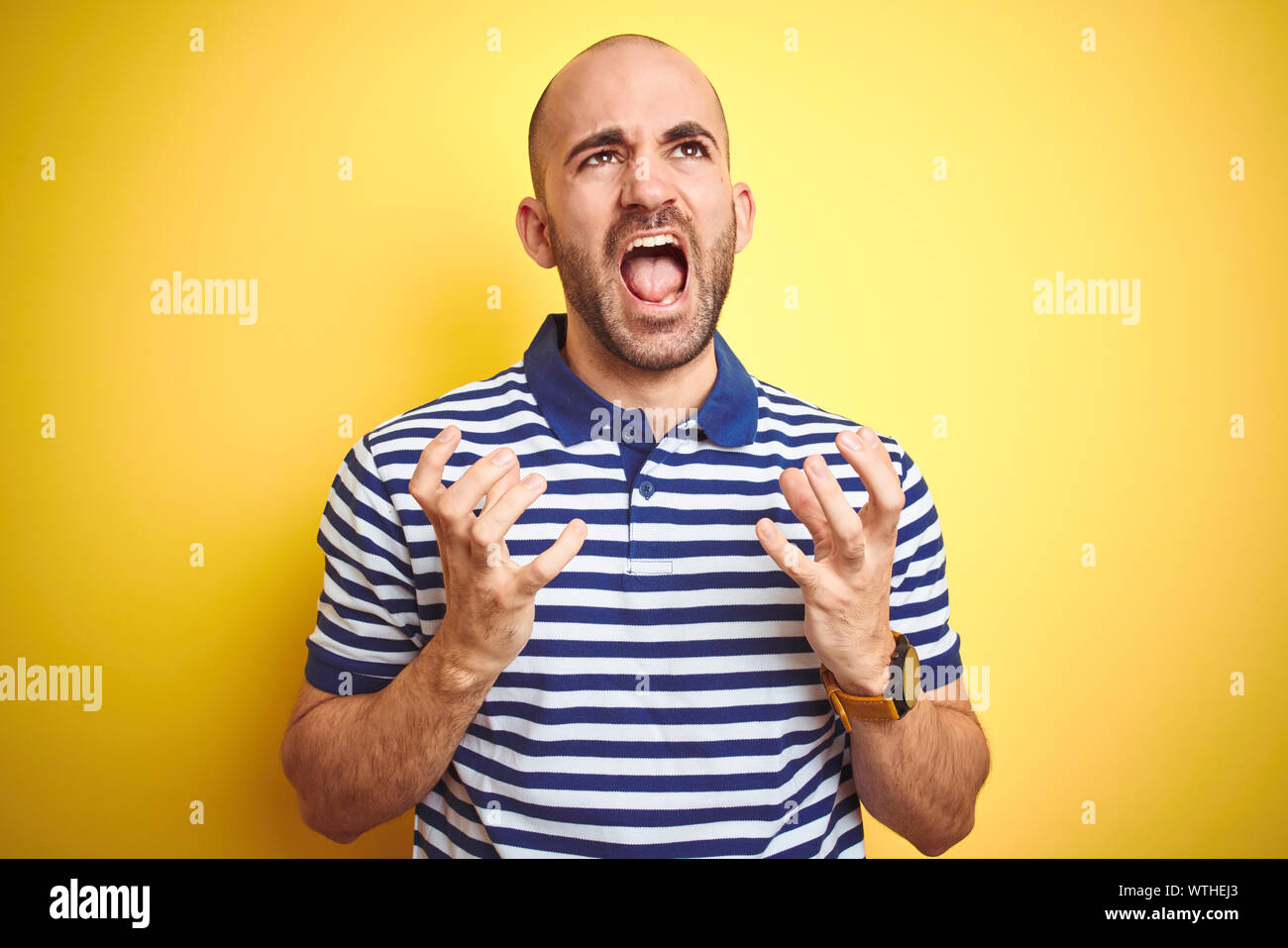 Young bald man with beard wearing casual striped blue t-shirt over ...