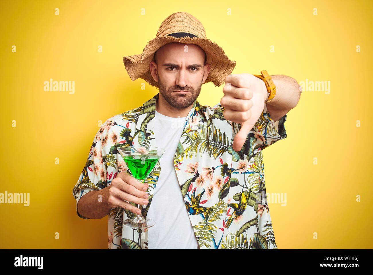 Young man wearing summer hawaiian flowers shirt and drinking a cocktail ...