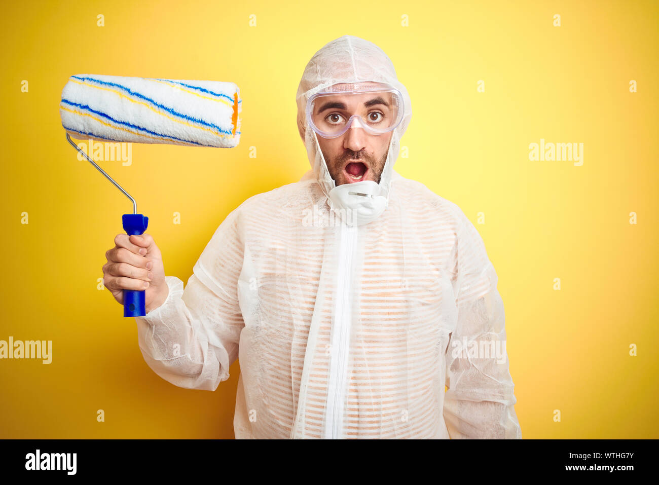 Young man wearing painter equipment and holding painting roller over ...