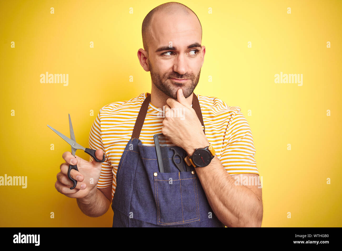 Young hairdresser man wearing barber apron holding scissors over ...