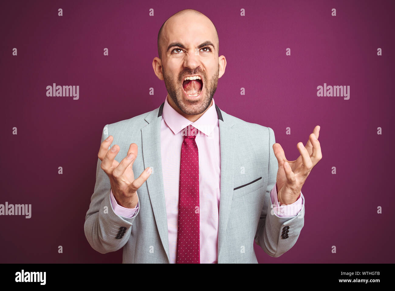 Young business man wearing suit and tie over purple isolated background ...