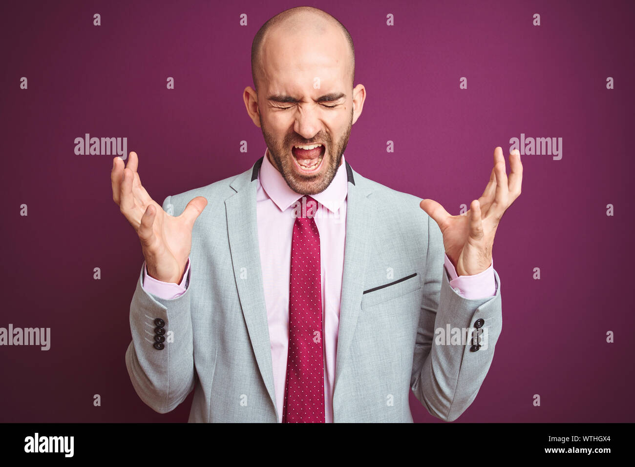 Young business man wearing suit and tie over purple isolated background ...