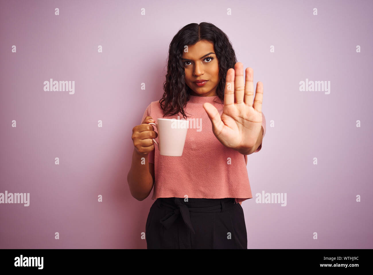 Transsexual transgender woman drinking cup of coffee over isolated pink ...