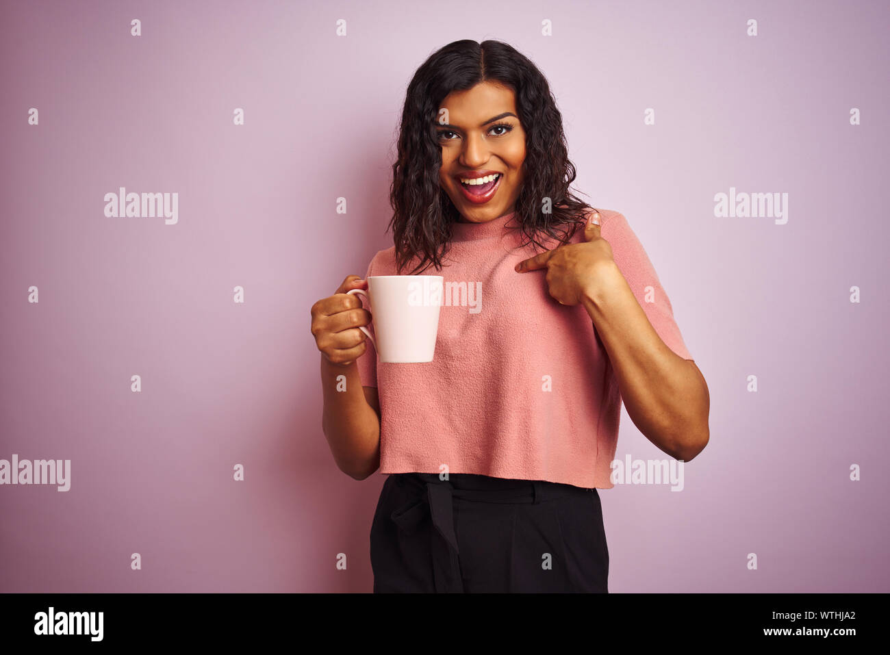 Transsexual transgender woman drinking cup of coffee over isolated pink ...