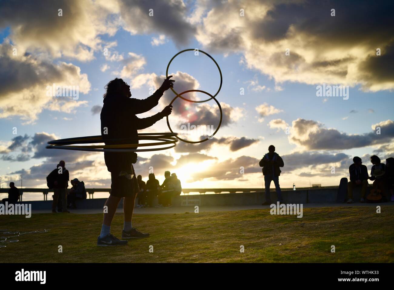 Man practicing spinning rings hoops in park, with bohemian, hippie ...