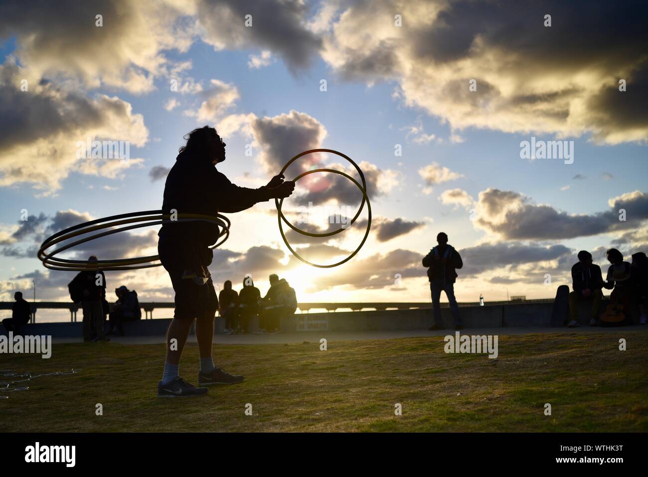 Man practicing spinning rings hoops in park, with bohemian, hippie ...
