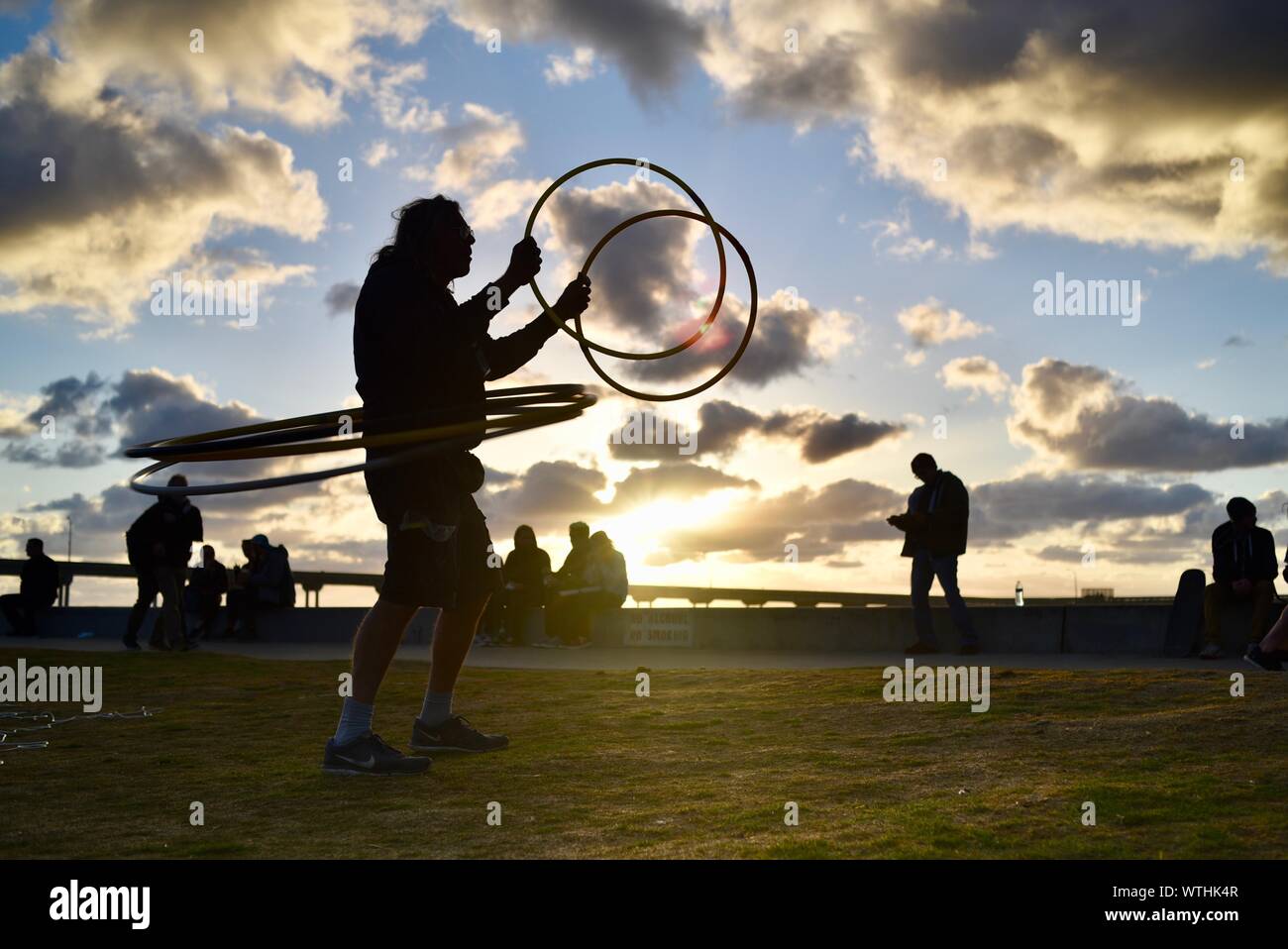 Man practicing spinning rings hoops in park, with bohemian, hippie ...