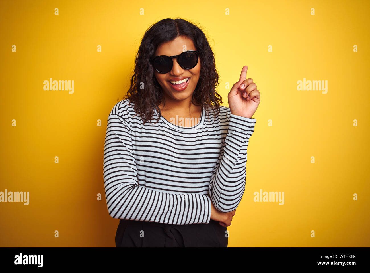 Transsexual transgender woman wearing sunglasses over isolated yellow ...