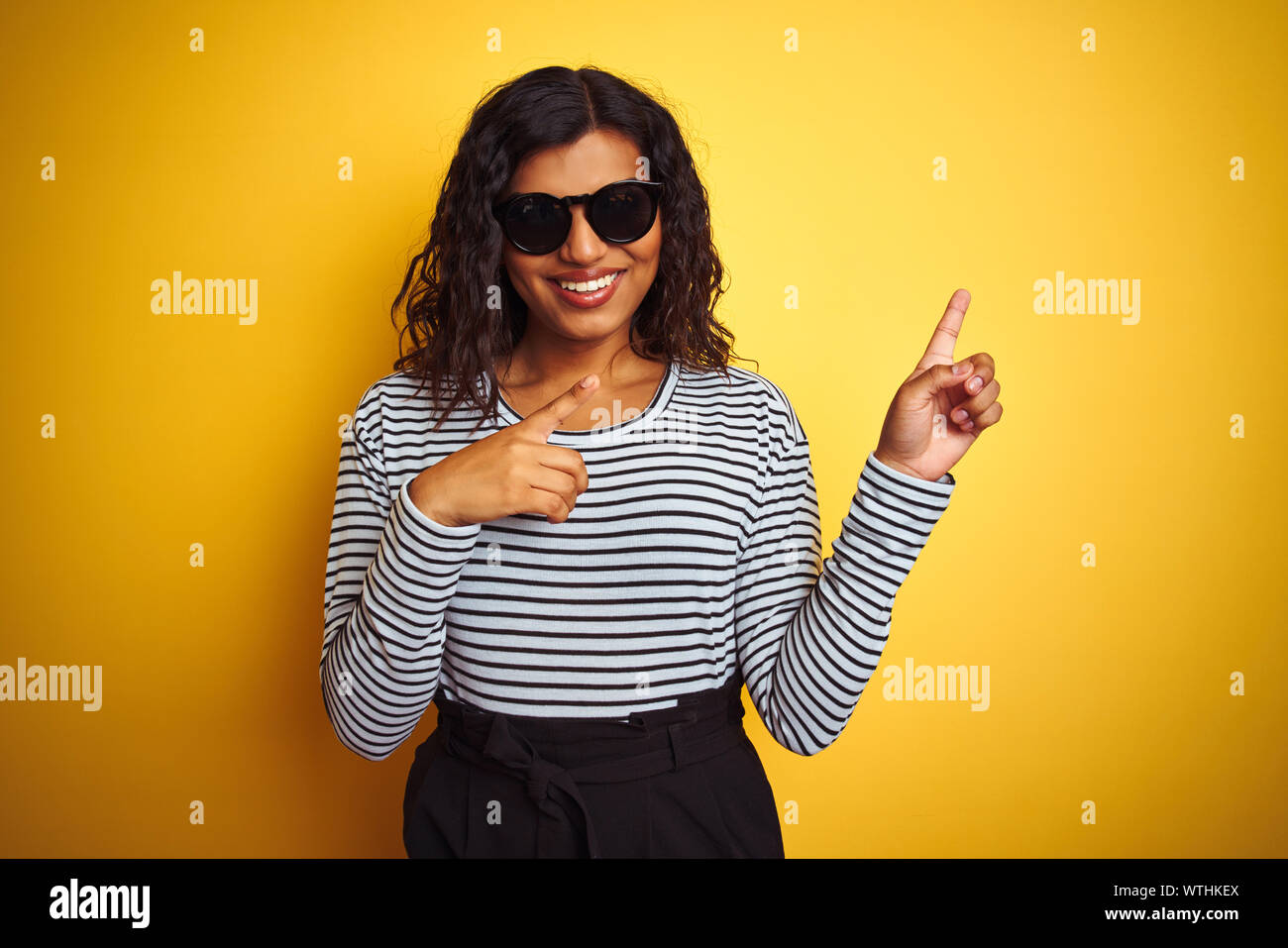 Transsexual transgender woman wearing sunglasses over isolated yellow ...