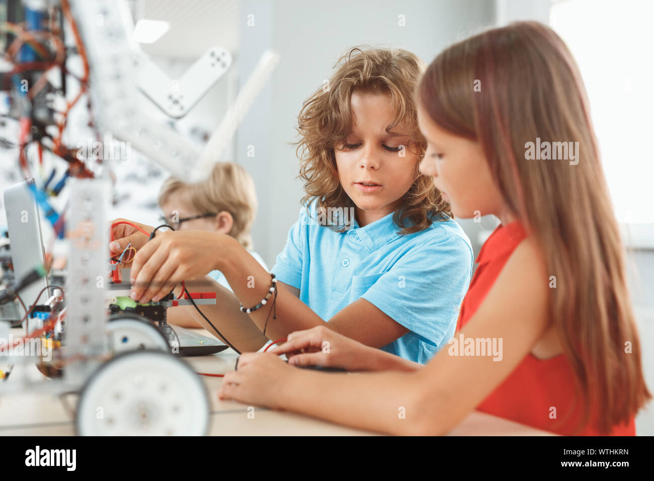 Robotics. Children sitting having class working on robot concentrated ...