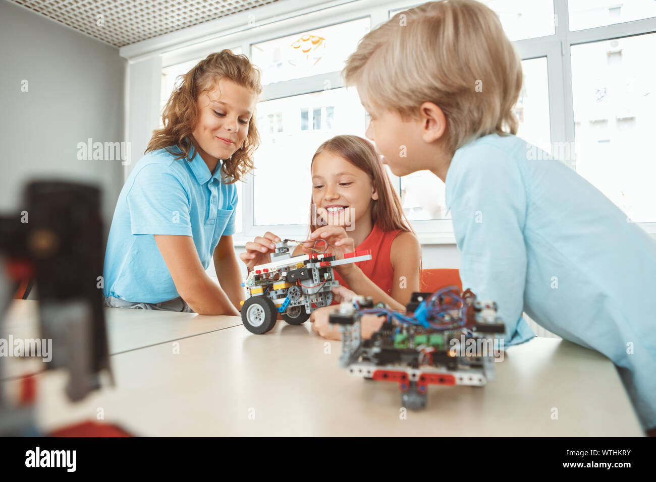 Robotics. Children having class sitting making robots connecting wires ...