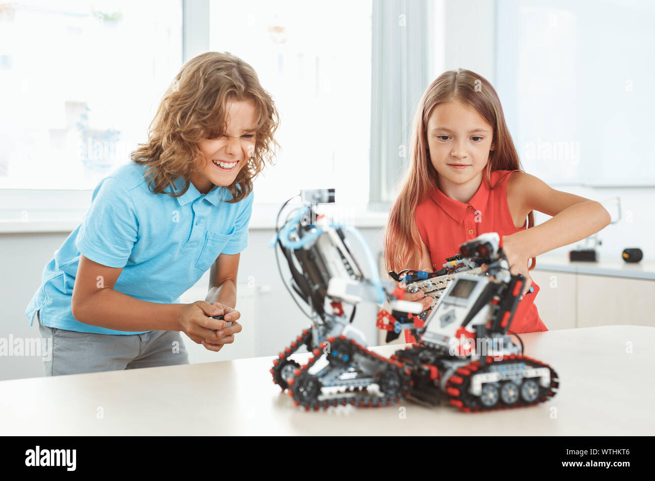 Robotics. Children holding controllers having robots fight laughing ...