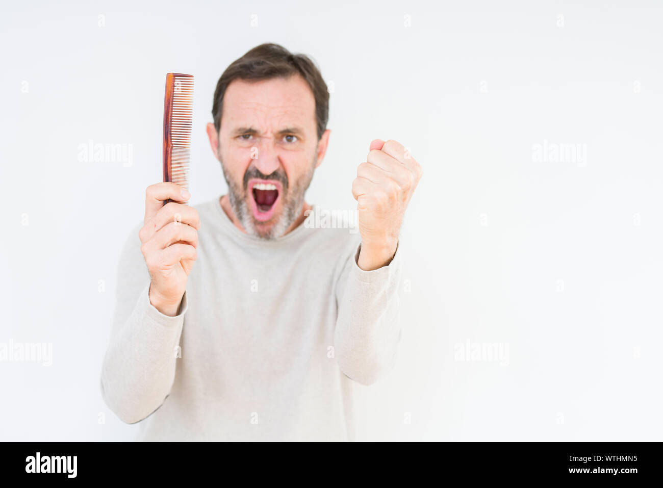 Senior man holding hair comb over isolated background annoyed and ...