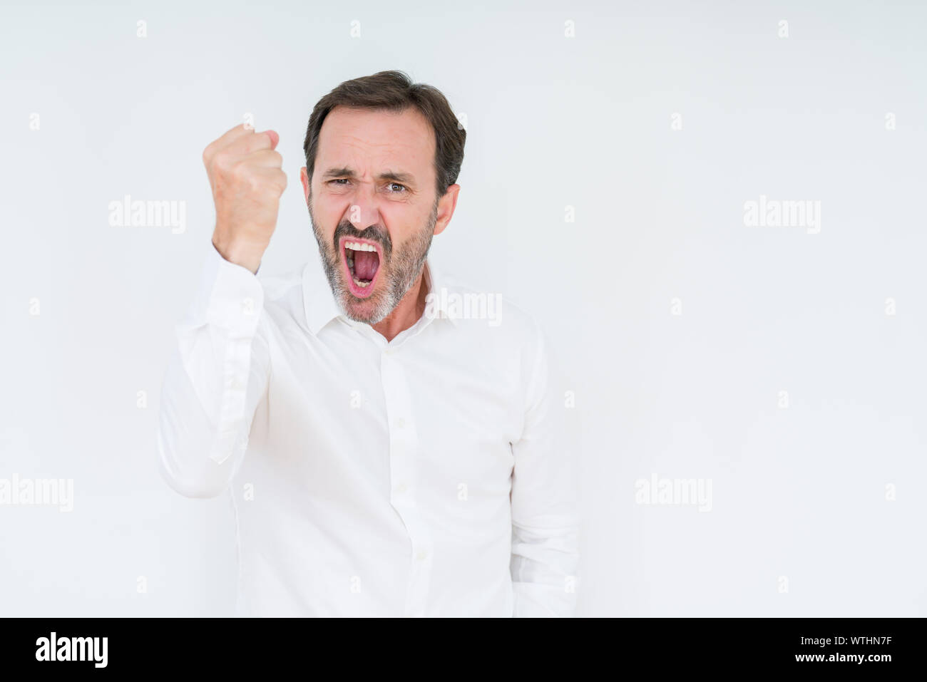 Elegant senior man over isolated background angry and mad raising fist ...