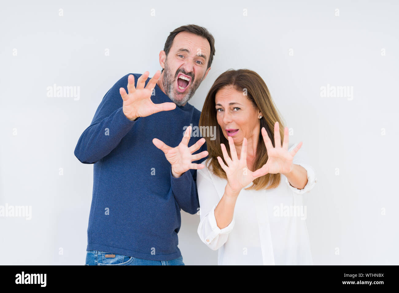 Beautiful middle age couple in love over isolated background afraid and ...
