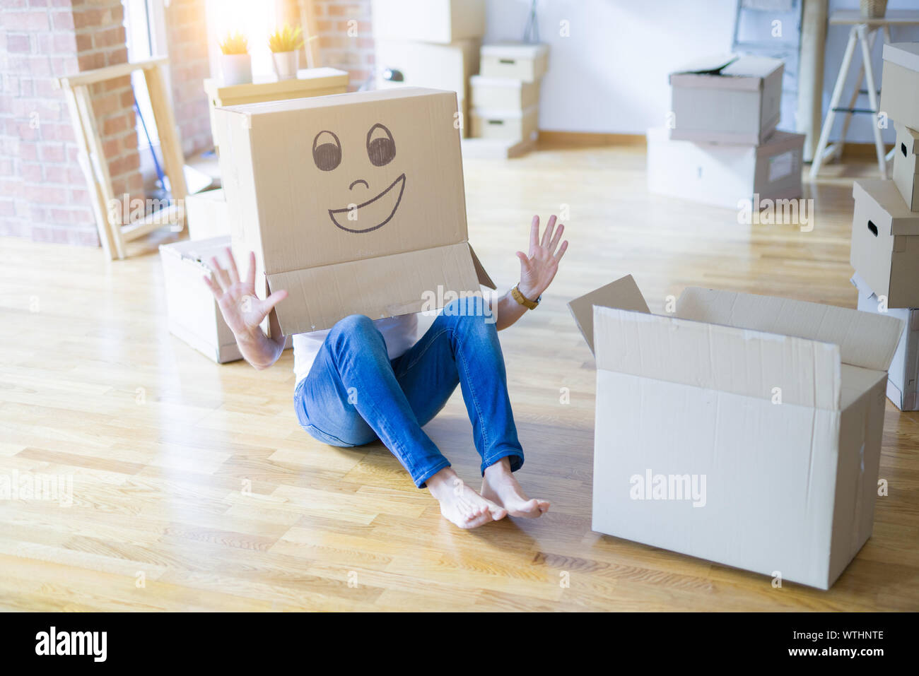 Man wearing funny cardboard box with happy face, moving to a new house ...