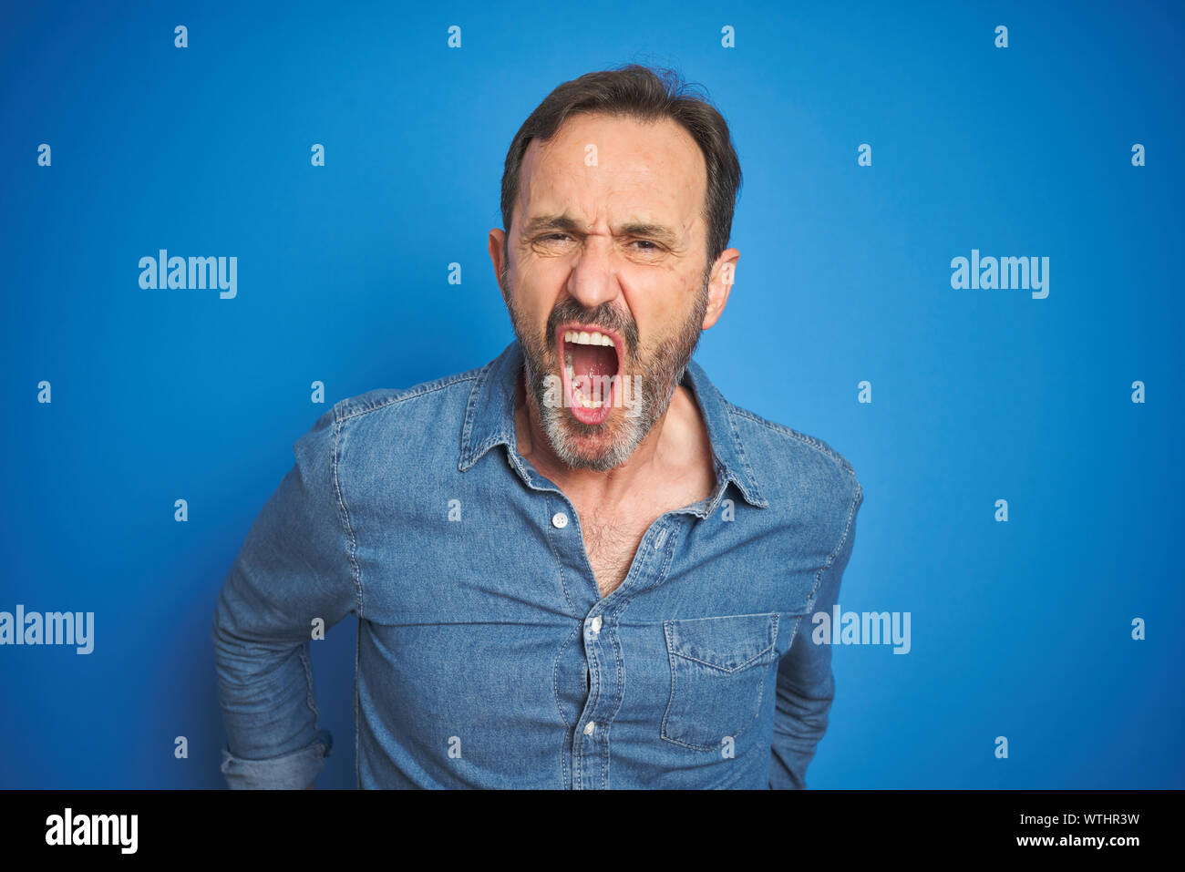 Handsome middle age senior man with grey hair over isolated blue ...