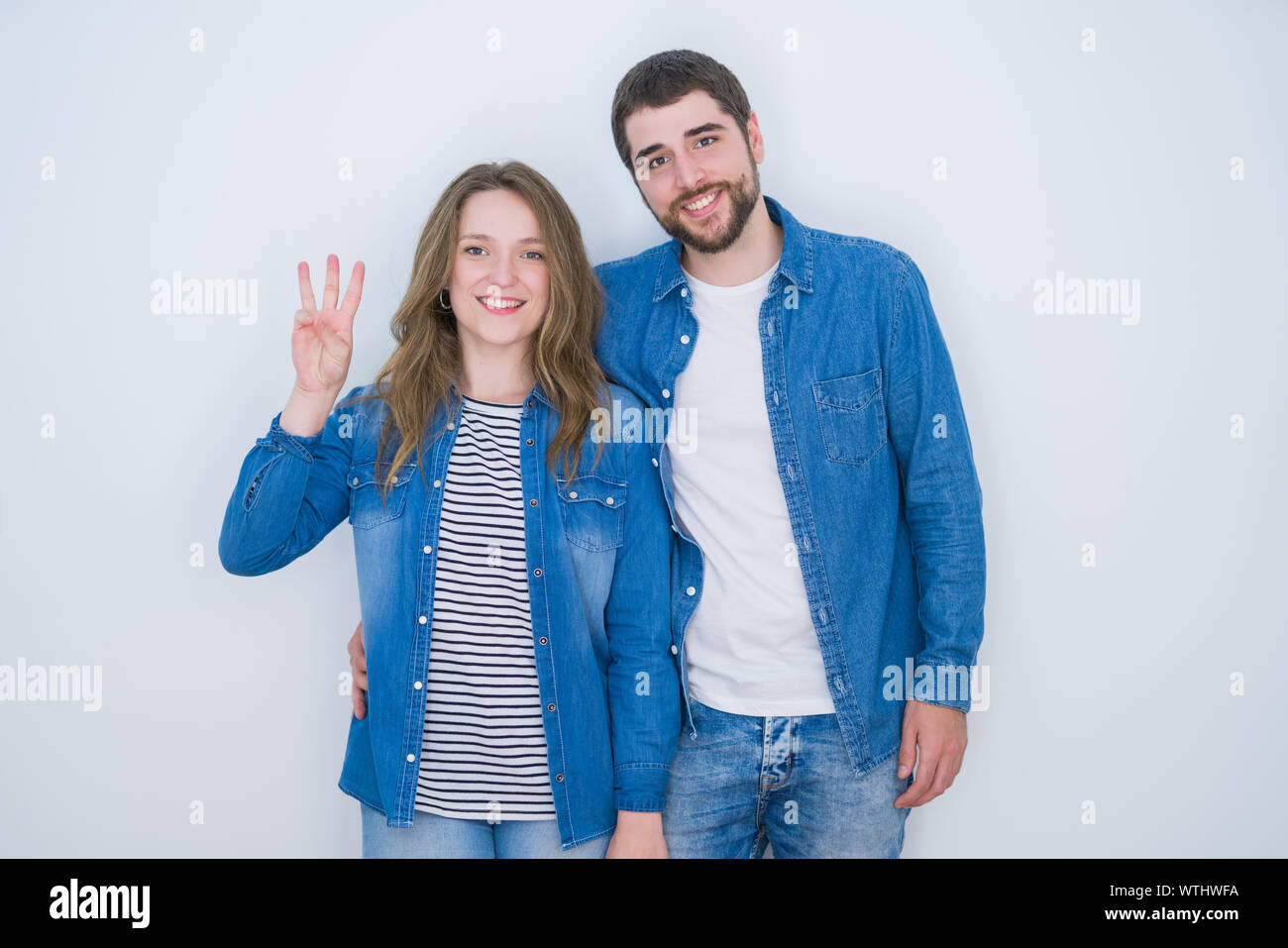 Young beautiful couple standing together over white isolated background ...