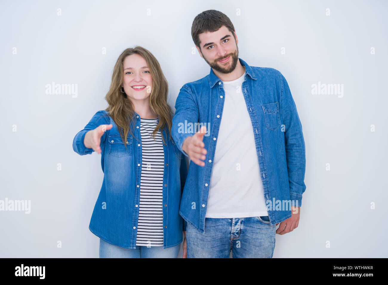 Young beautiful couple standing together over white isolated background ...