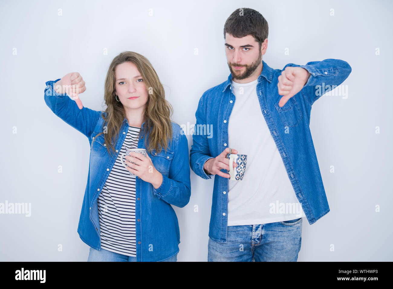 Young beautiful couple drinking a cup of coffee over white isolated ...