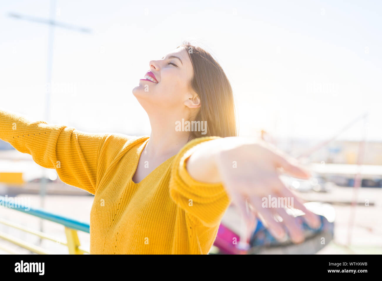 Beautiful young woman smiling with closed eyes and open arms enjoying ...