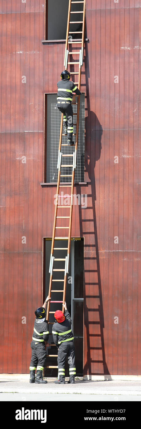 three fire fighters at firehouse and a long wodden laddder Stock Photo ...