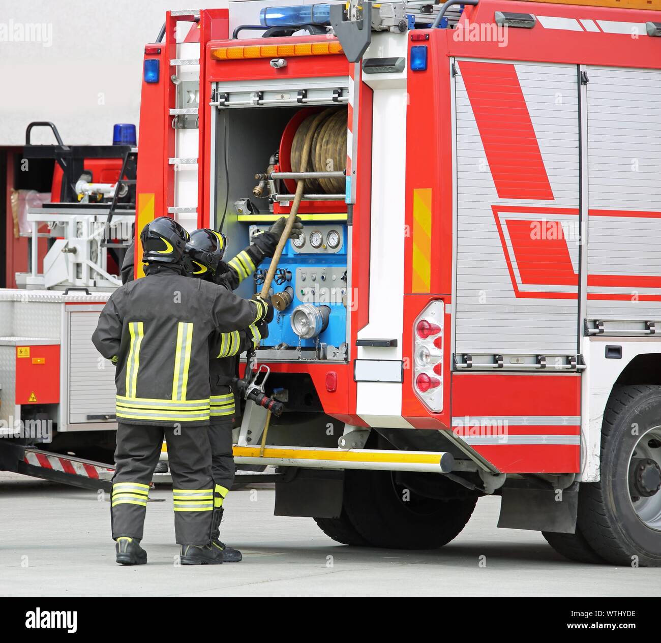 fire engine and two firemen in action during the fire Stock Photo - Alamy