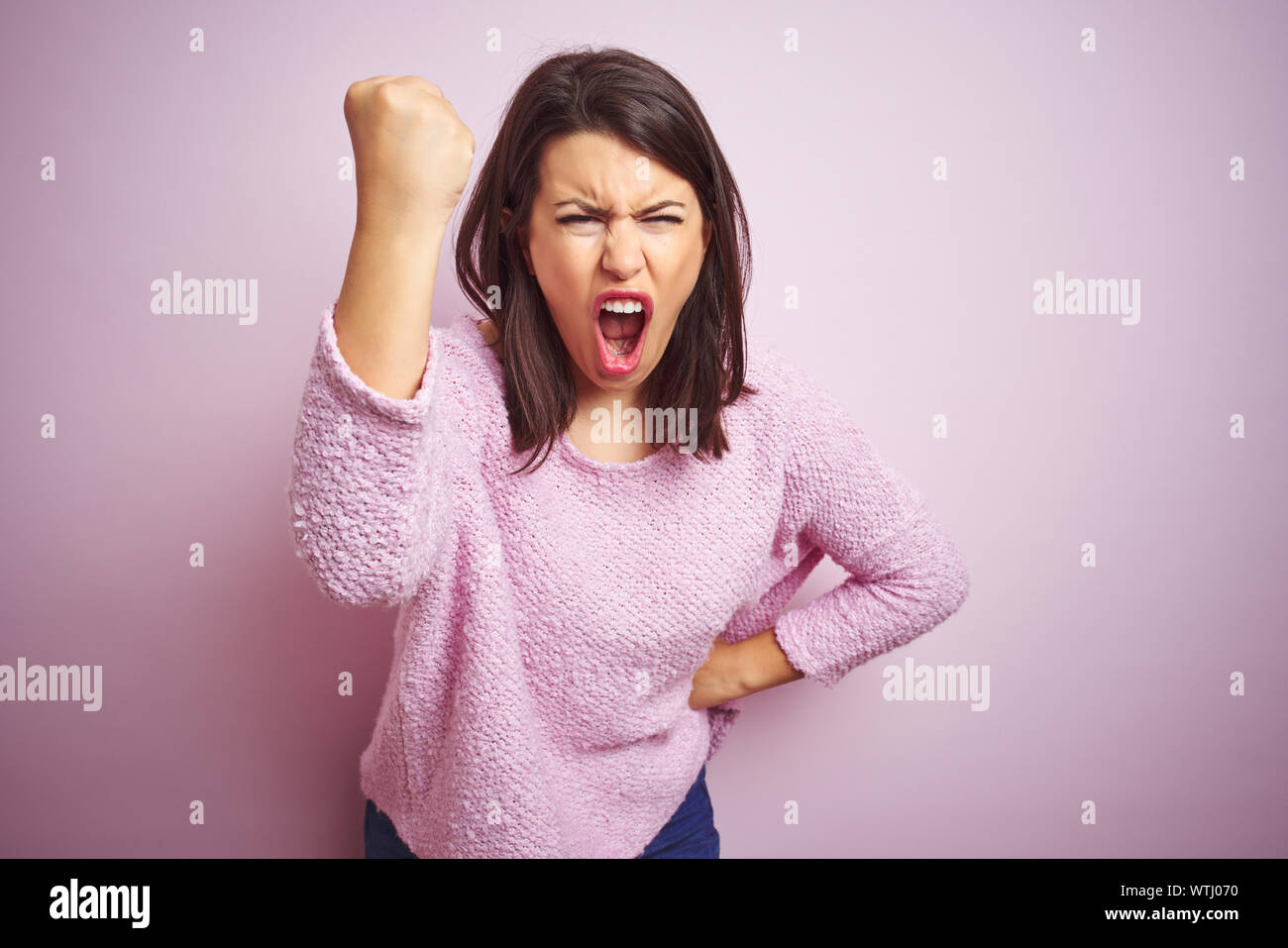Young beautiful brunette woman wearing a sweater over pink isolated ...