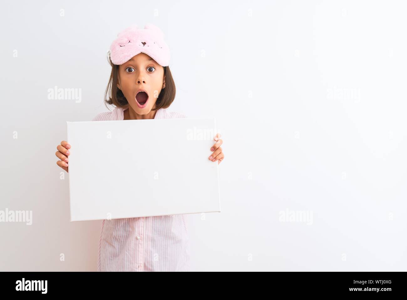 Child girl wearing sleep mask and pajama holding banner over isolated ...