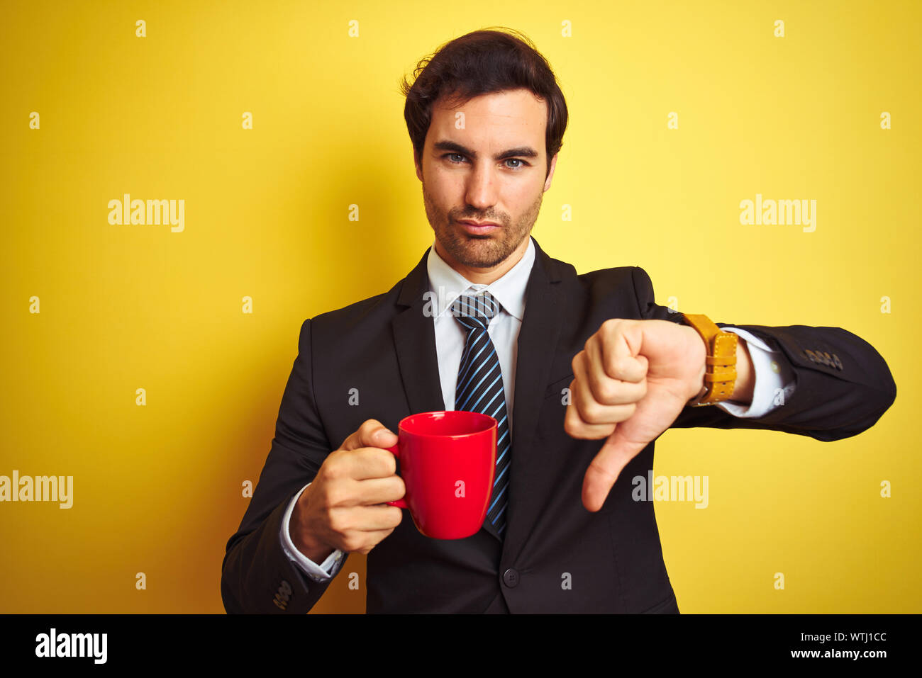 Young handsome businessman drinking red cup of coffee over isolated ...