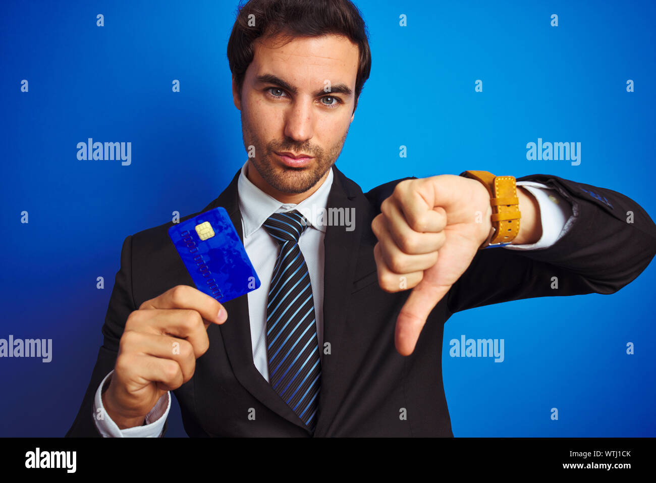 Young handsome businessman holding credit card standing over isolated ...
