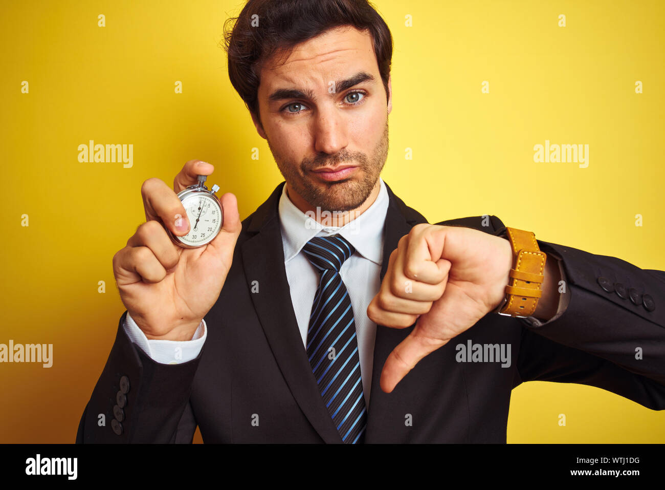 Young handsome businessman holding stopwatch standing over isolated ...