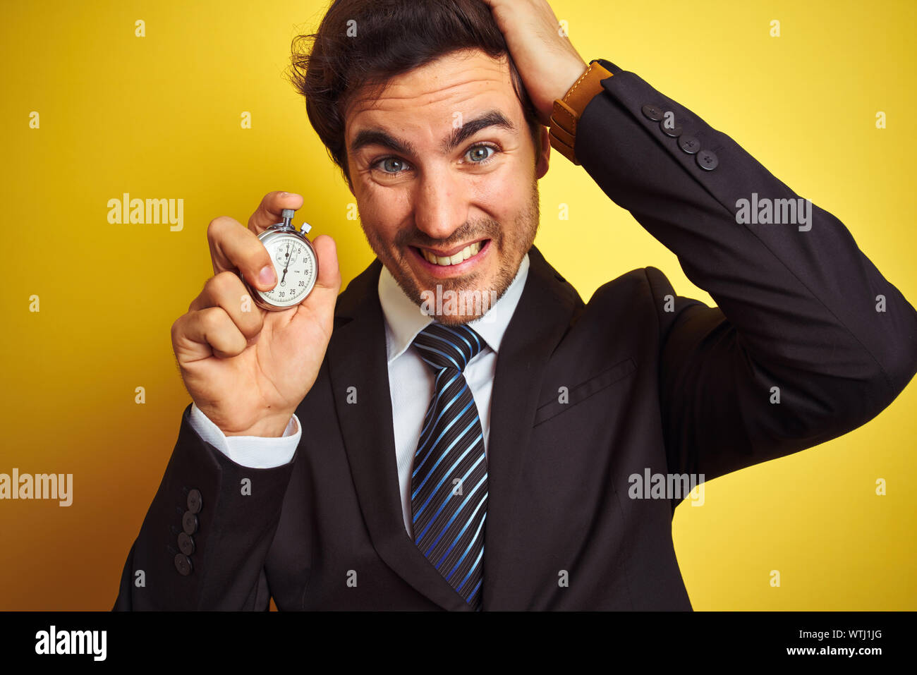Young handsome businessman holding stopwatch standing over isolated ...